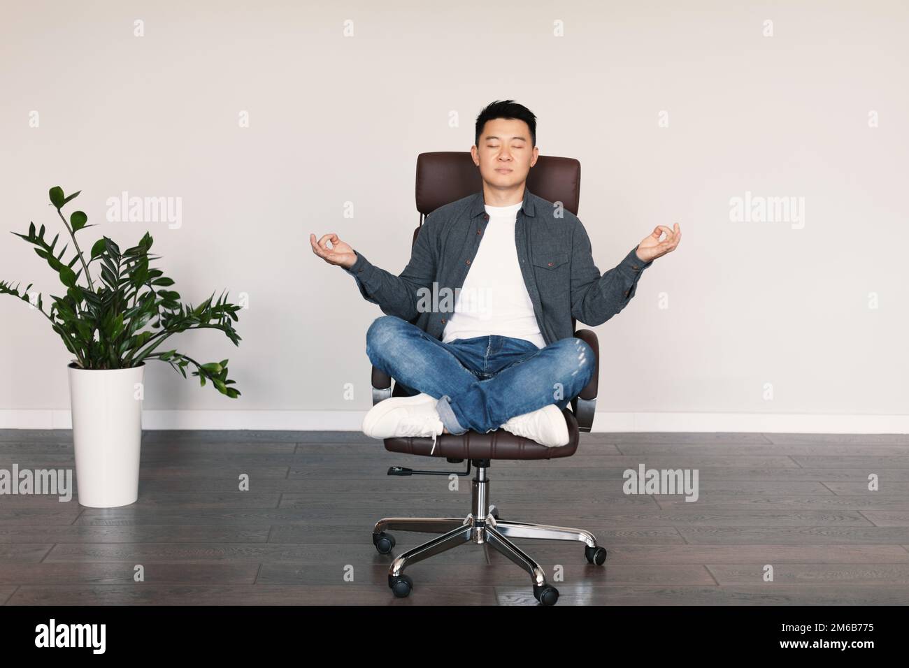 Serious calm adult asian male with closed eyes sits in armchair ...