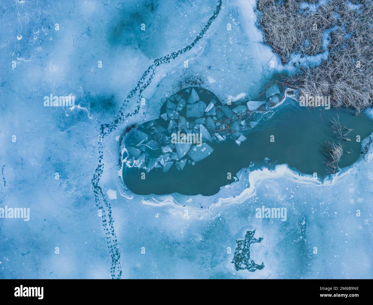 Panoramic aerial view of a frozen lake with animal tracks and cracked ...