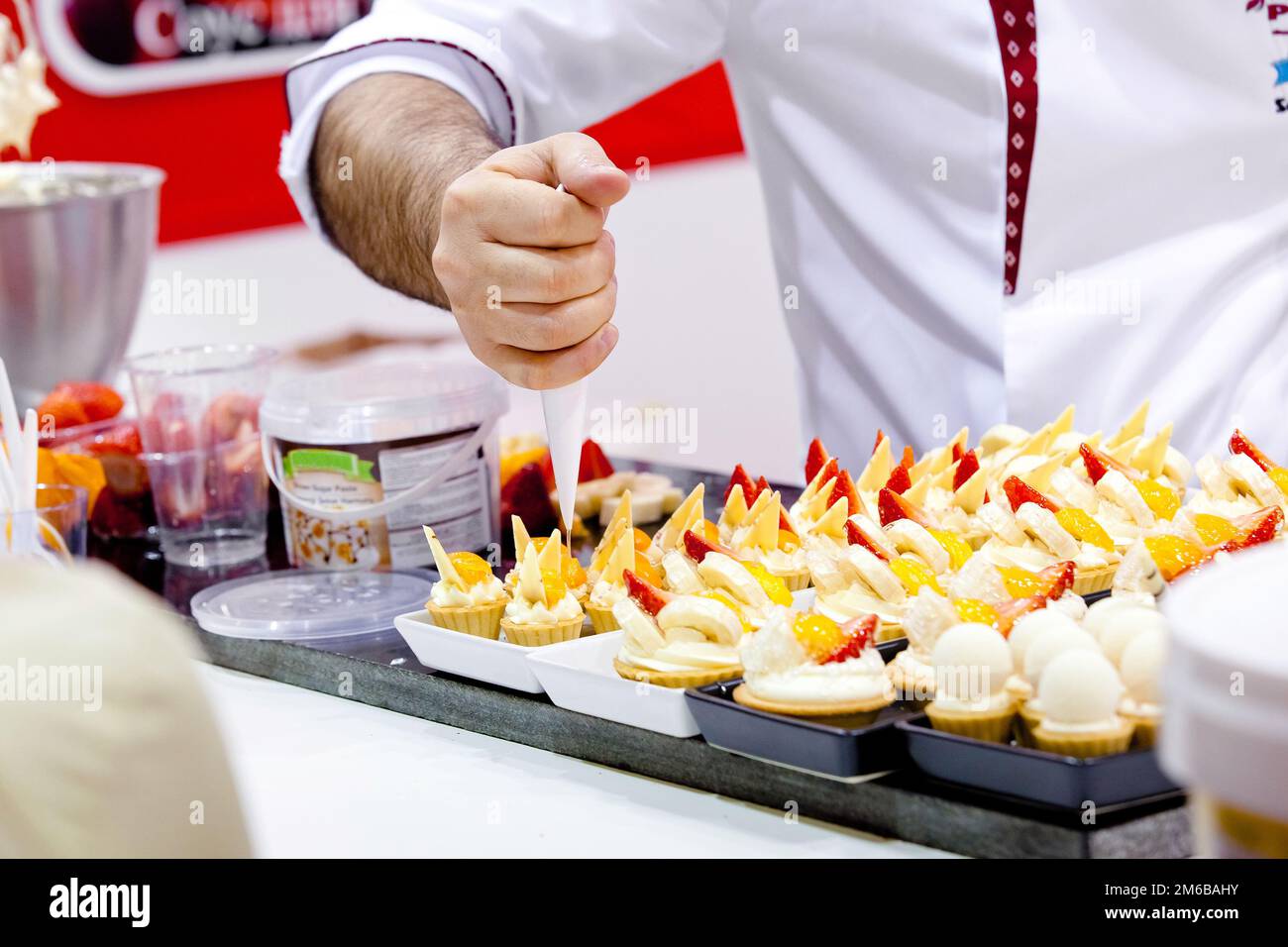 Chef with cooking bag decorating cupcakes cream Stock Photo - Alamy