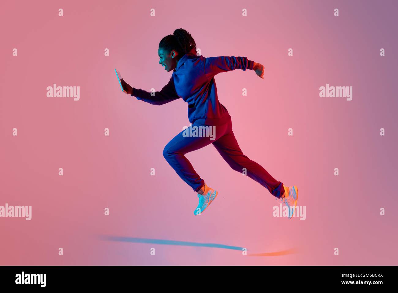 Full body length shot of modern sporty lady jumping or running using ...