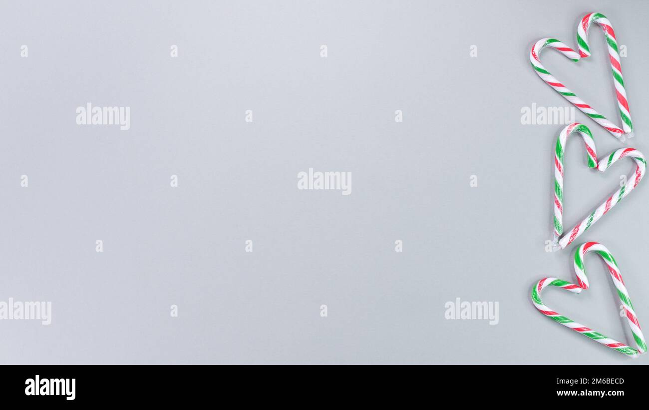 Red, green and white candy canes in the shape of heart on grey ...