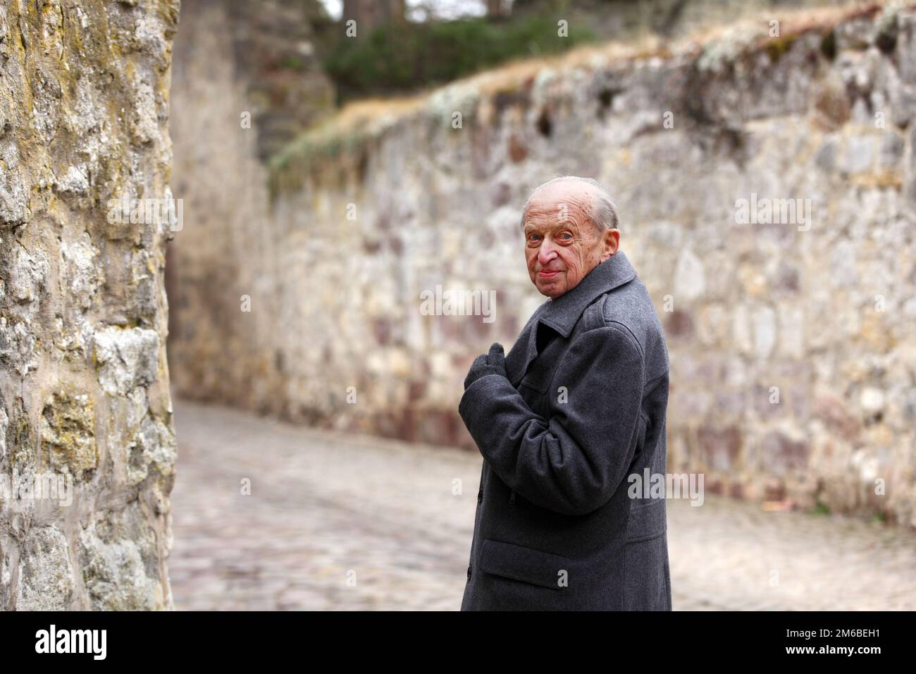 Elderly man standing at the city walls of a historic German town and ...
