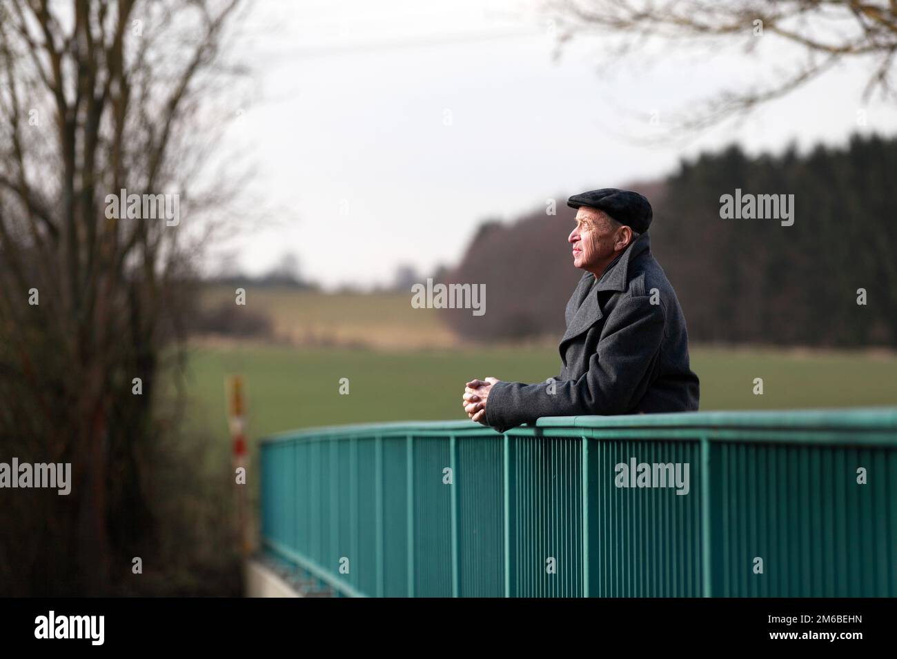 Elderly man praying at the handrail of a bridge Stock Photo - Alamy