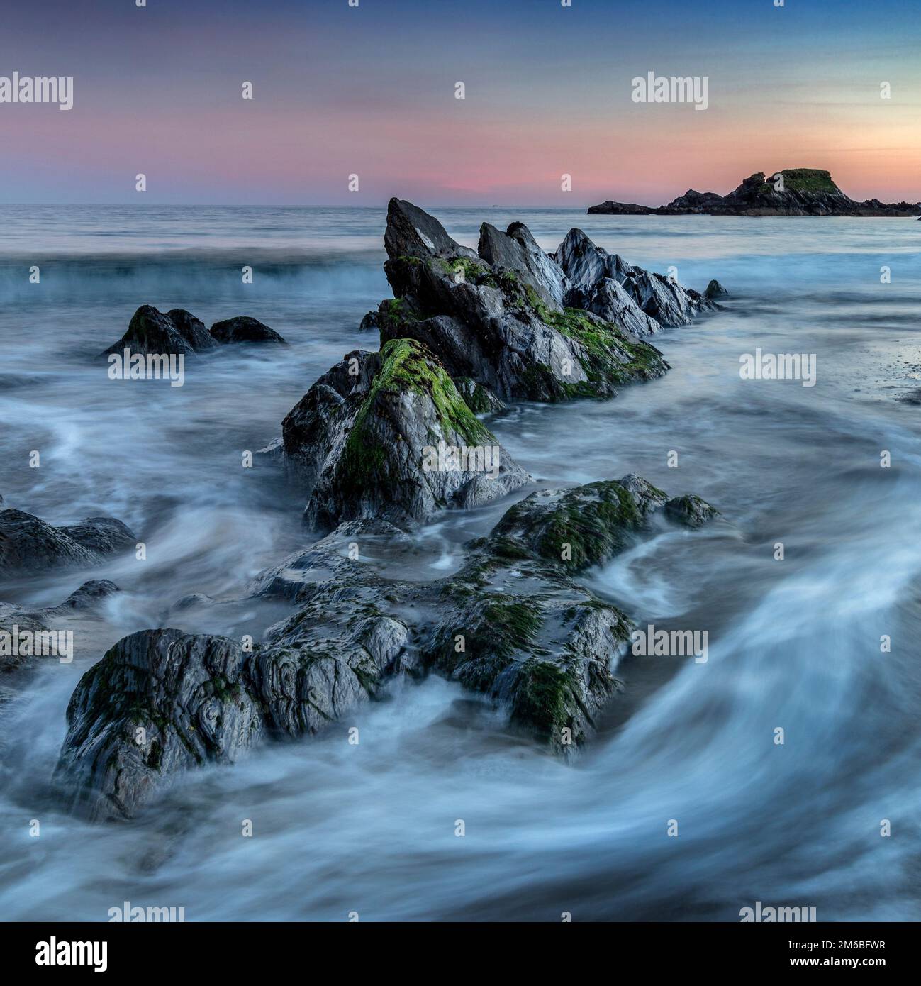 The rocks in the sea at sunset near the Long Strand, Ireland Stock ...