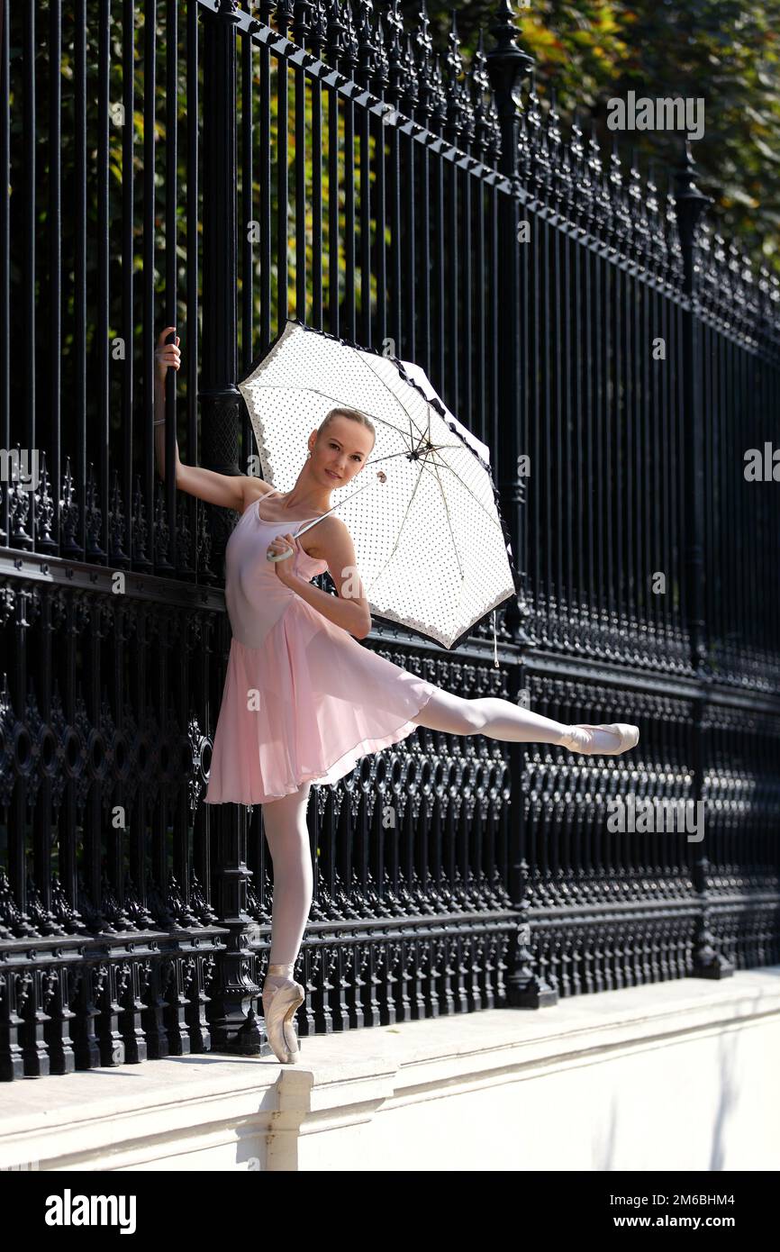 Beautiful ballerina with umbrella dancing at an iron fence Stock Photo ...