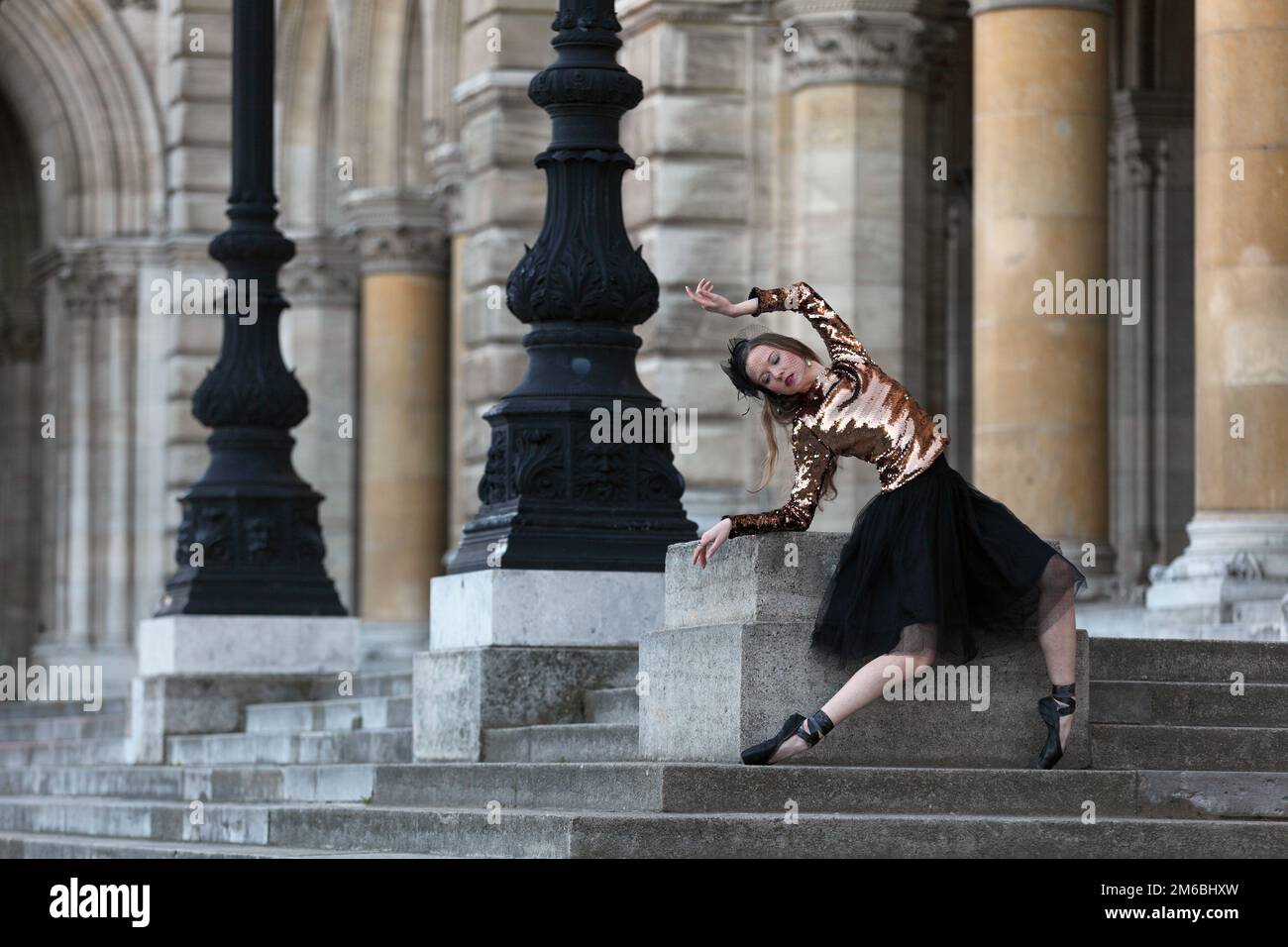 Elegant ballerina in black skirt, haze and golden top dancing in front ...