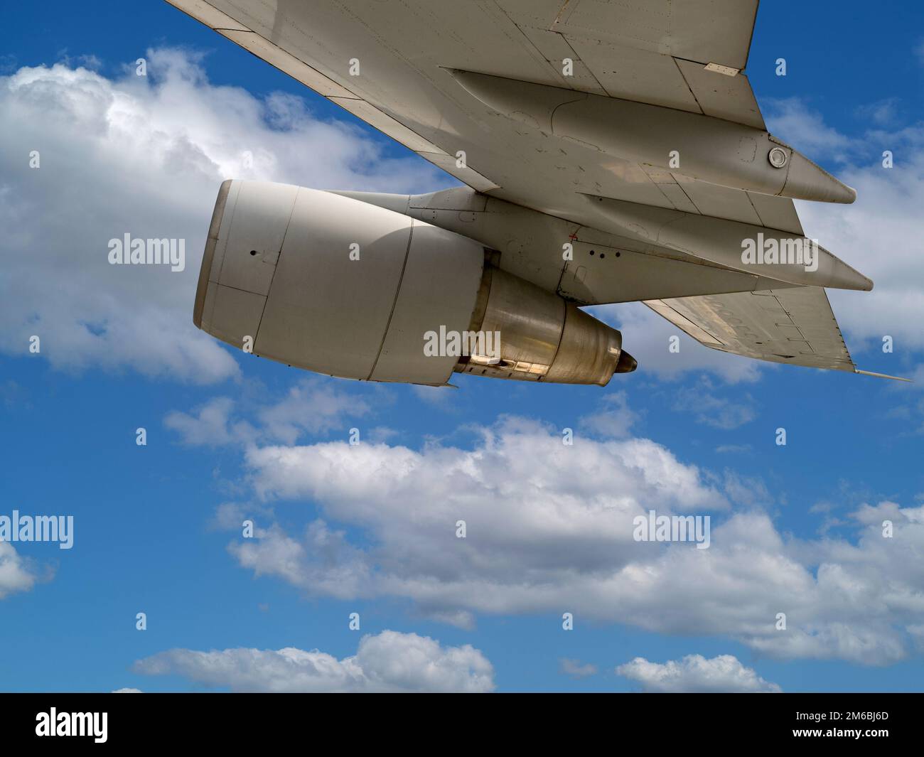 Wing and engine of a passenger jet in flight against a blue sky with ...