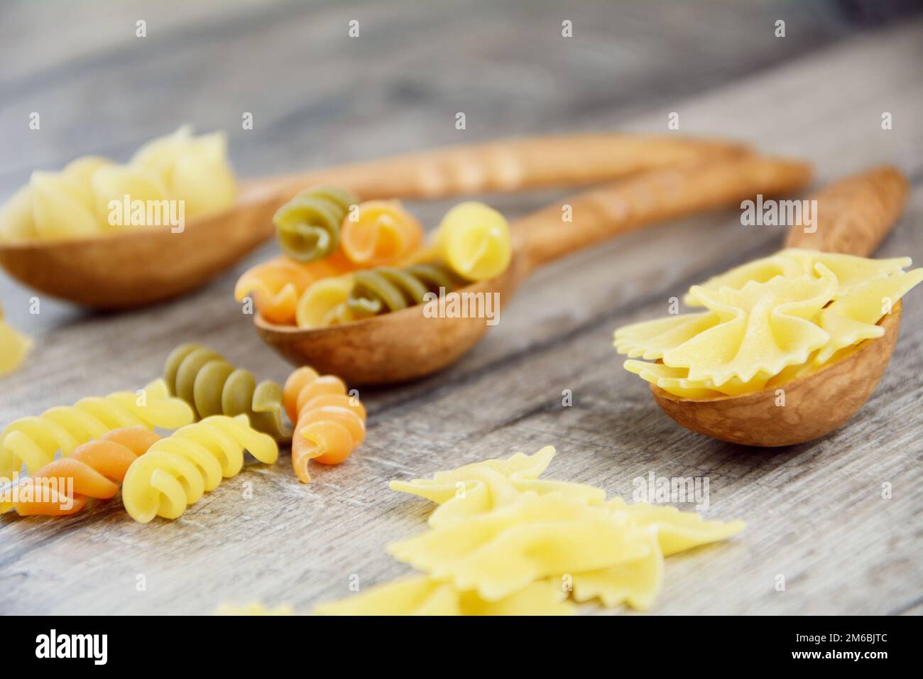 Three kinds of raw pasta in wooden spoons Stock Photo - Alamy
