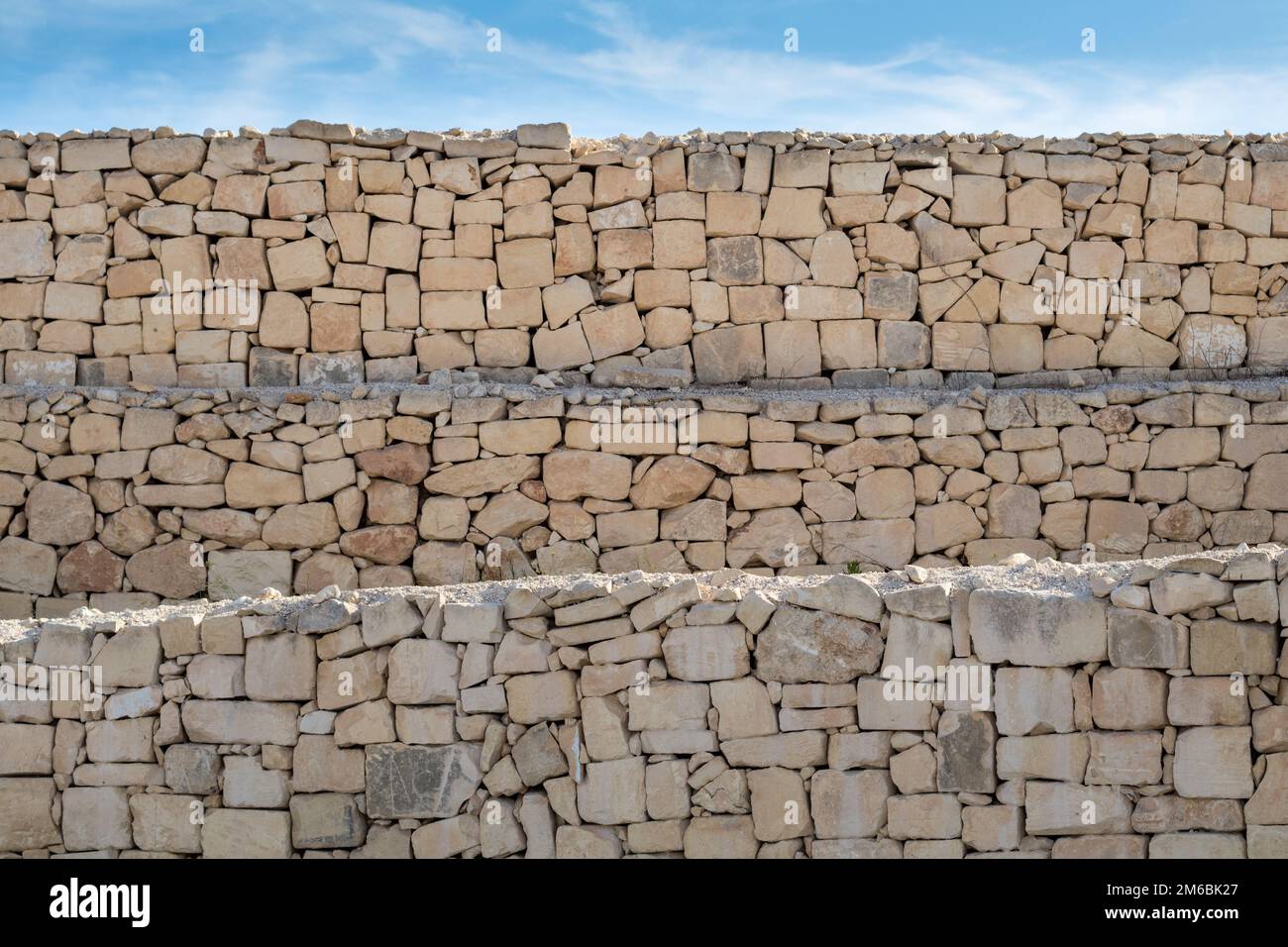 Limestone layered, rough dry stone wall, under a blue sky Stock Photo ...