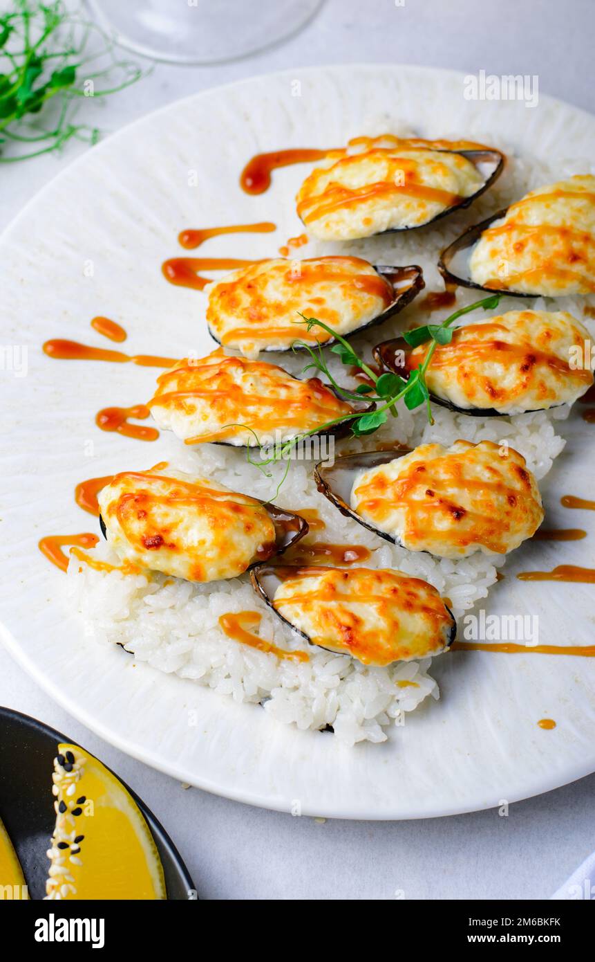 Baked mussels with cheese in shells on rice in a plate, gourmet dinner ...