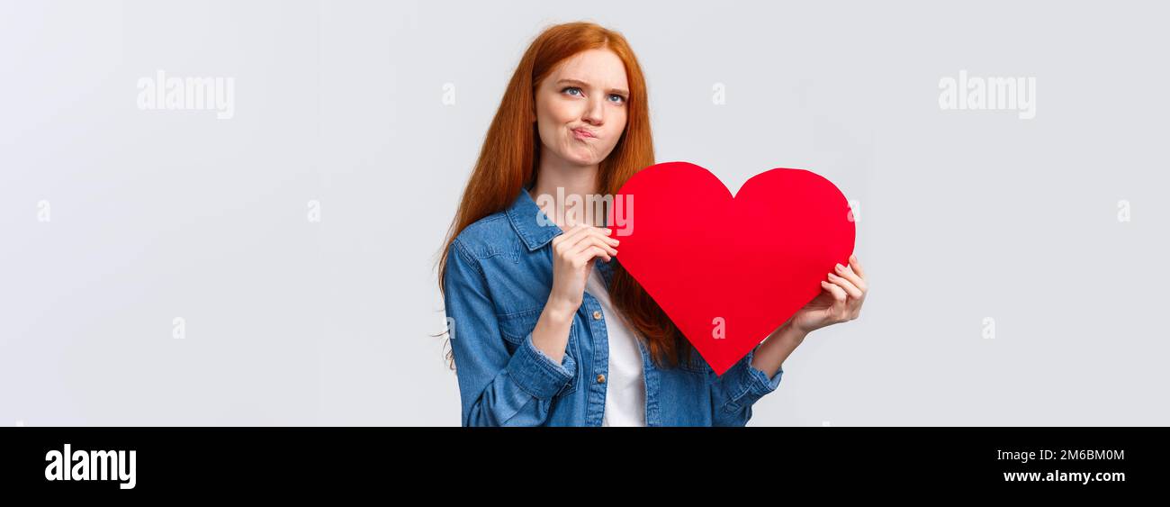 Thoughtful and focused, serious-looking redhead girl trying think ...