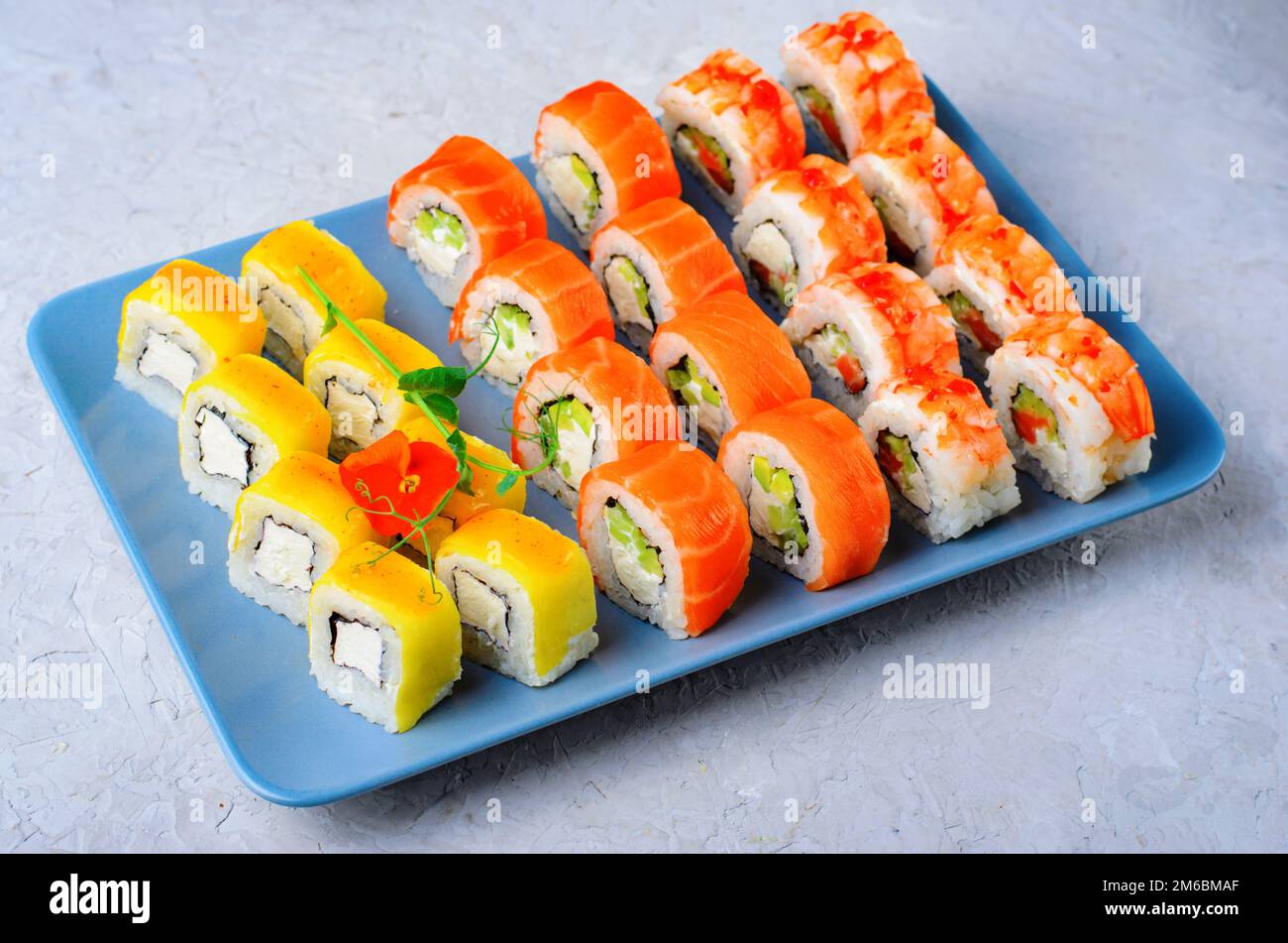 Sushi rolls set with salmon, shrimp and mango on light blue background ...