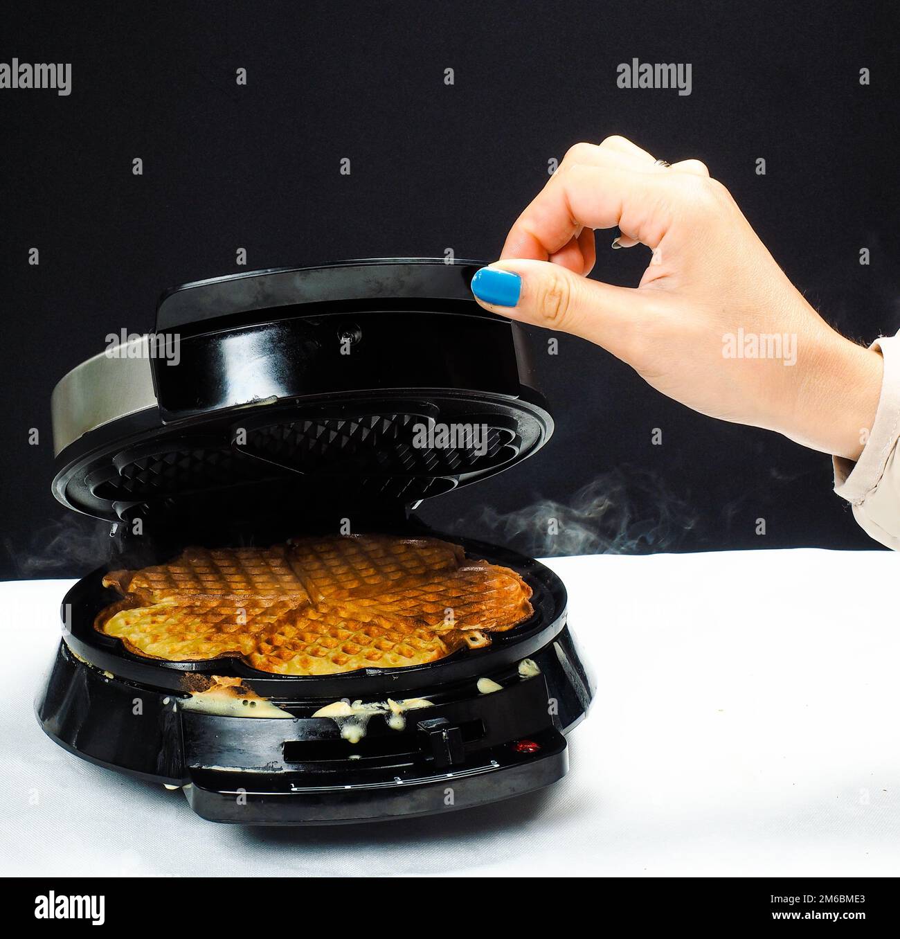 Person making steaming hot waffles with a waffle maker Stock Photo - Alamy