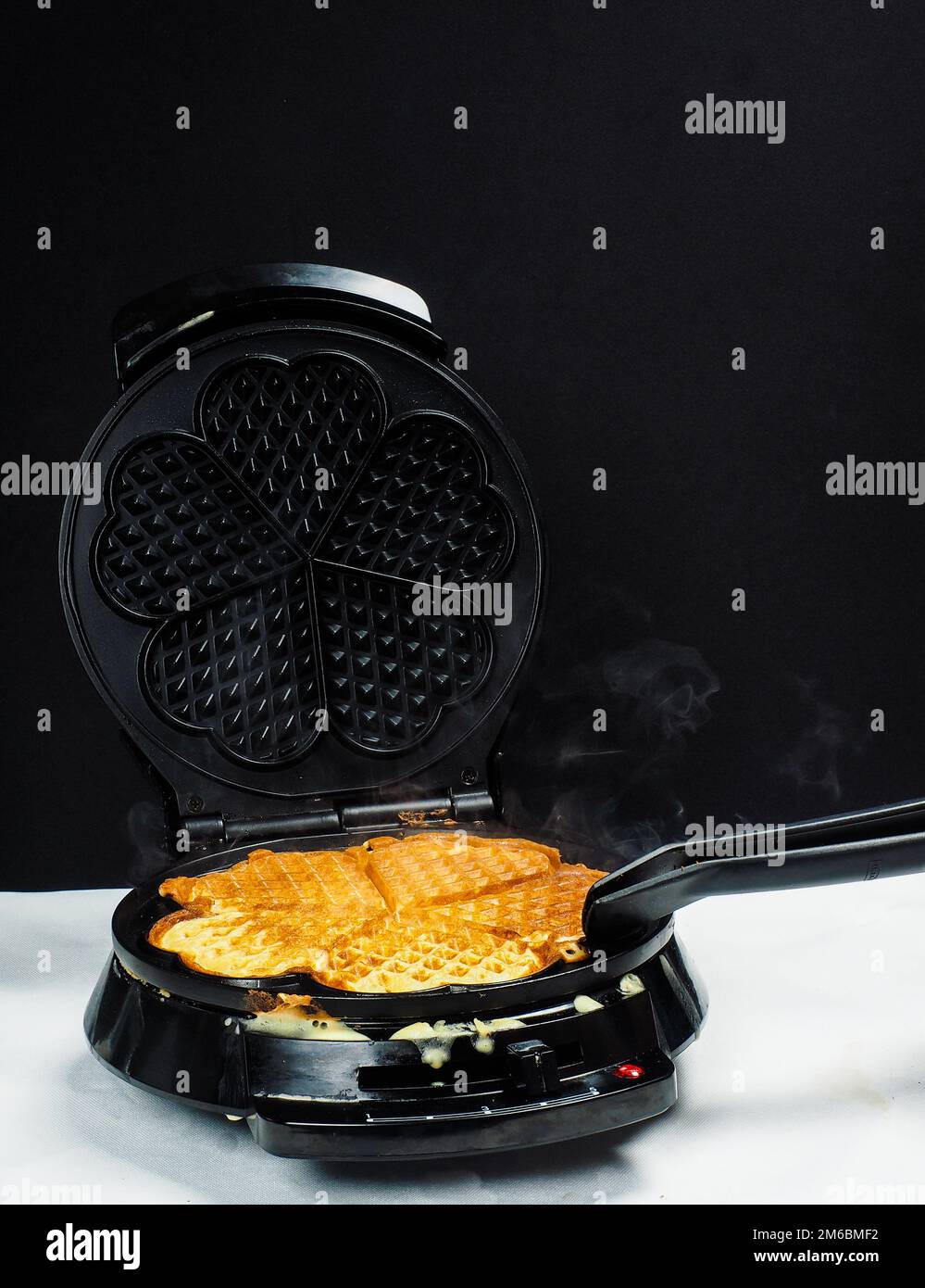 Making of waffles from a steaming hot machine Stock Photo - Alamy