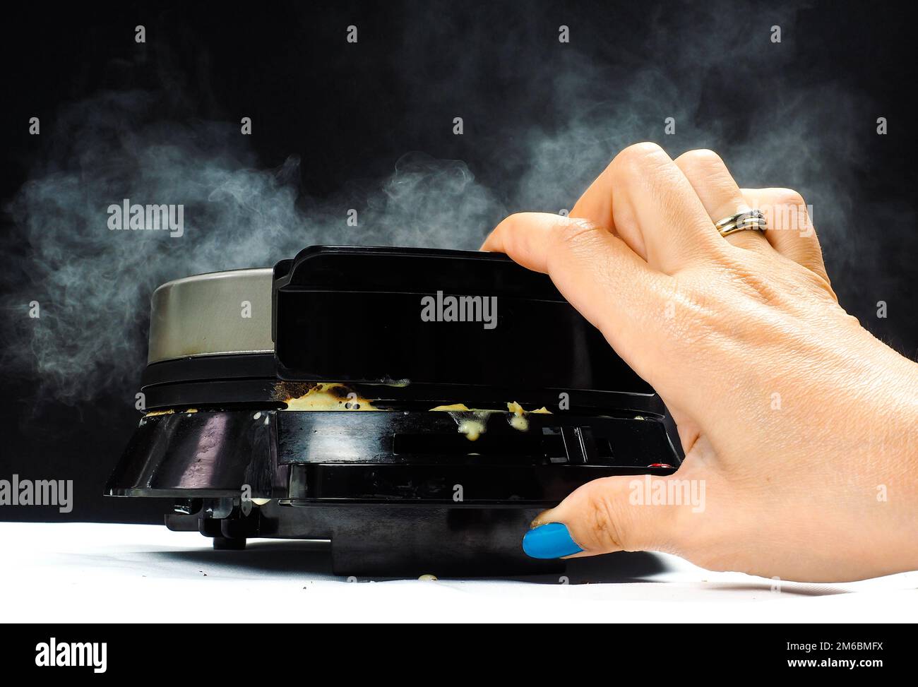 Female person pressing a steaming waffle maker Stock Photo - Alamy