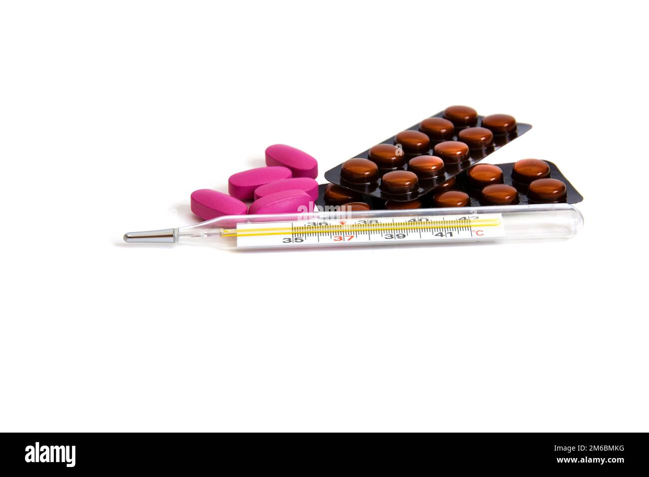 Medical thermometer to measure body temperature and pills on a white ...