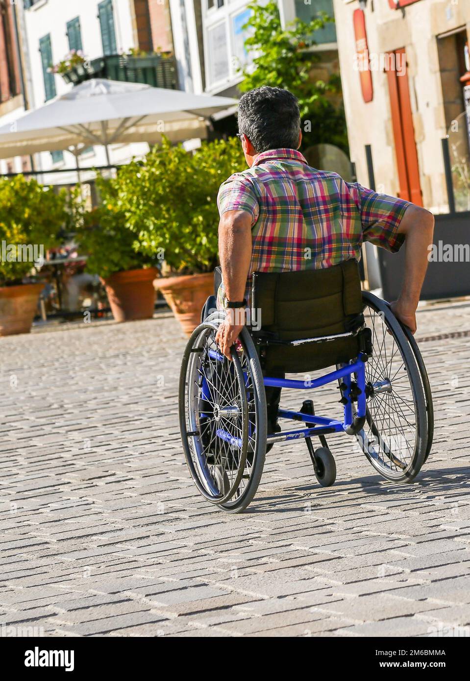 Disabled man rolling down the street in his wheelchair Stock Photo - Alamy