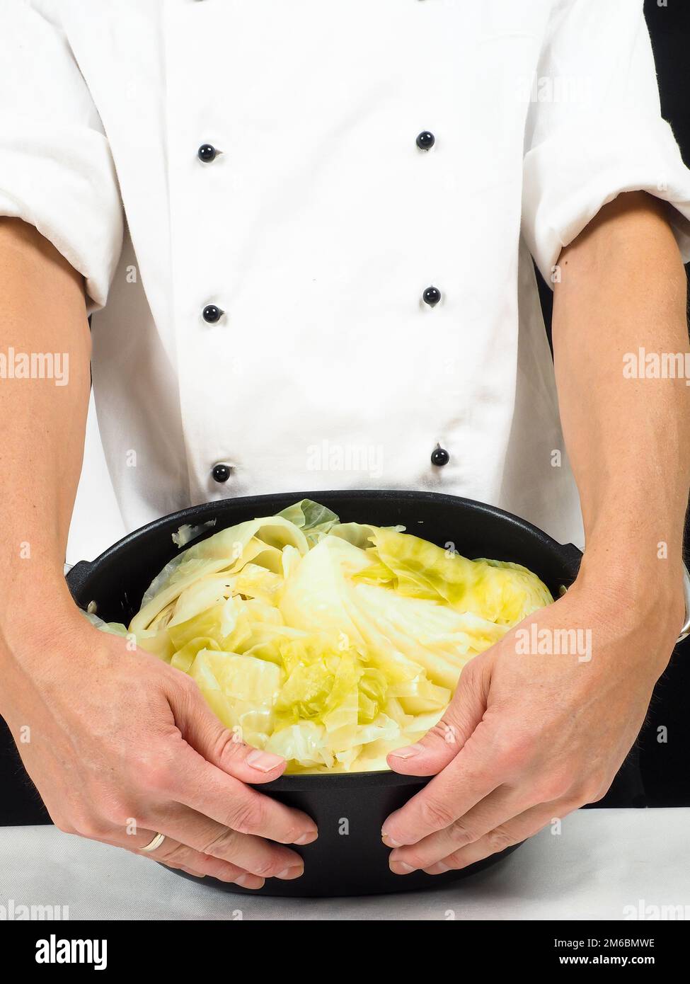 Chef in white jacket holding around a casserole of boiled cabbage Stock ...