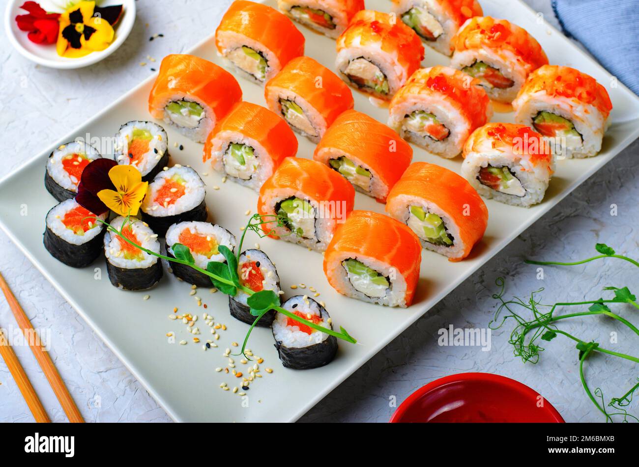 Sushi rolls set with salmon and shrimp on light blue background, Flower ...