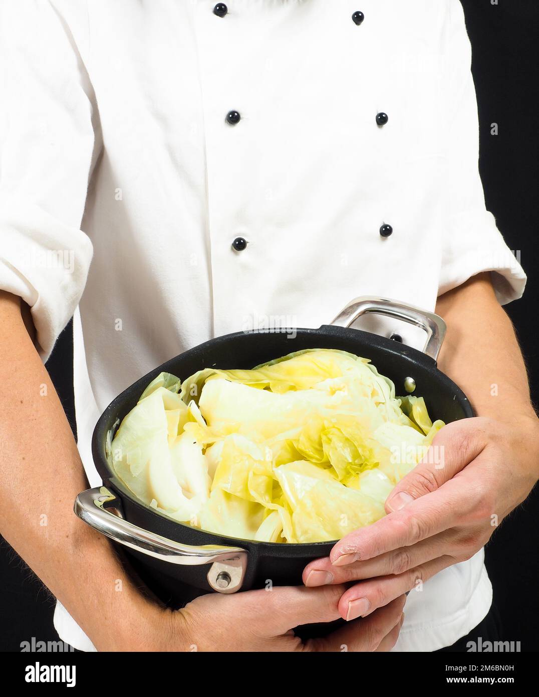 Chef in white jacket holding around a casserole of boiled cabbage Stock ...