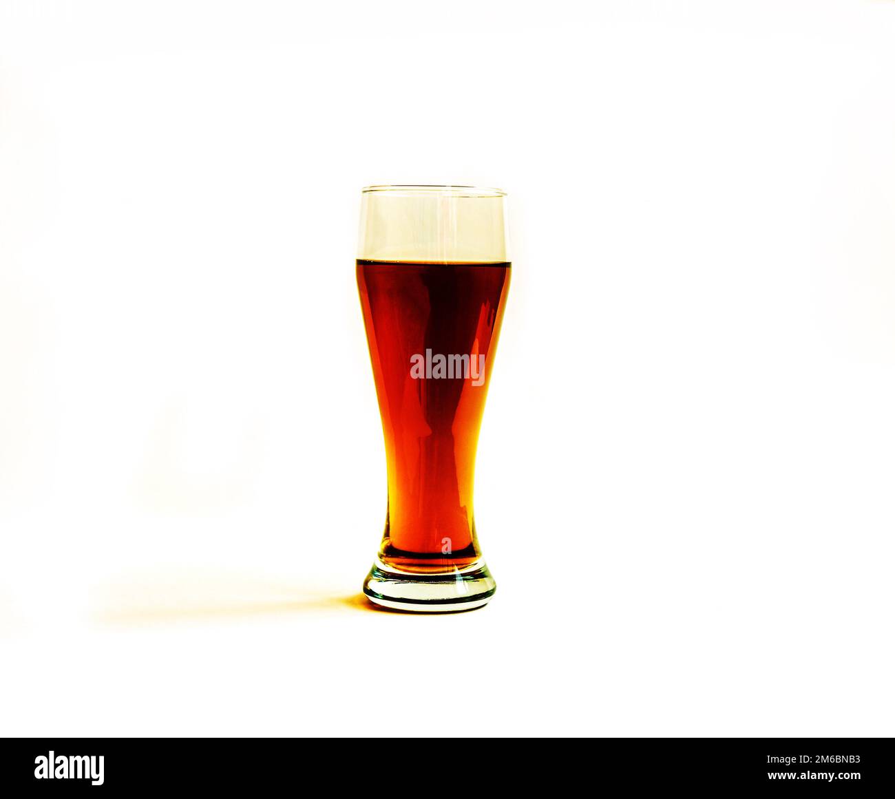 Tall glass beaker with liquid dark amber color on a white background ...