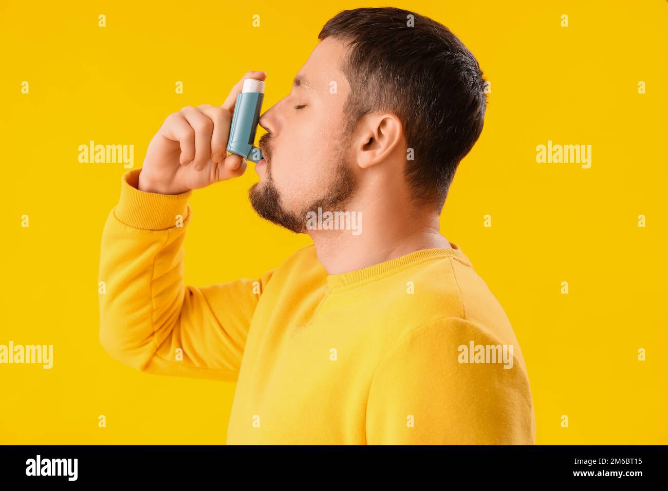 Sick man with inhaler on yellow background Stock Photo - Alamy