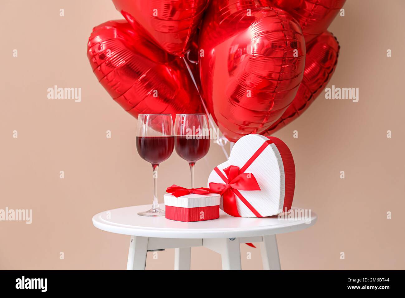 Table with glasses of wine, gifts and balloons for Valentine's Day near ...
