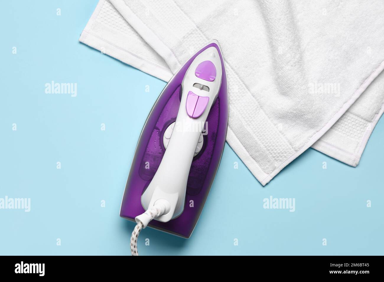 Electric iron and kitchen towel on light blue background Stock Photo ...
