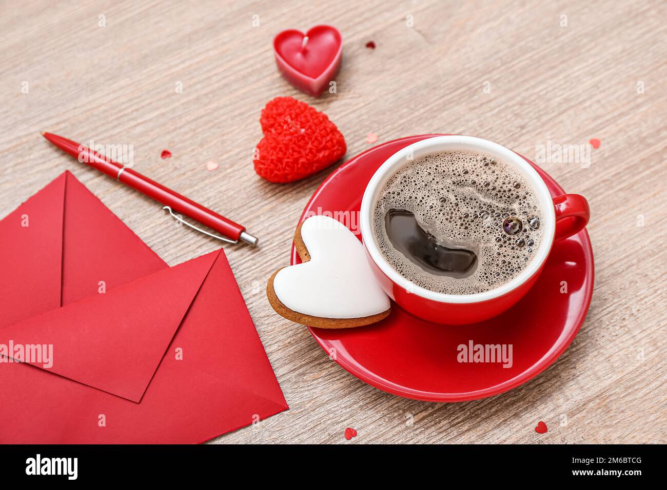 Cup of coffee with cookie, envelopes, candles and hearts on wooden ...