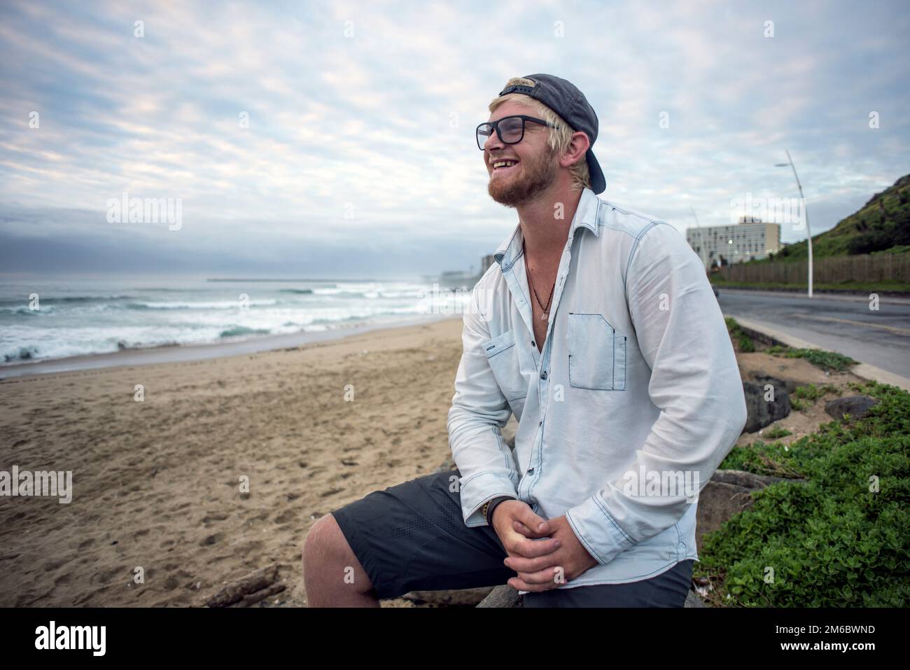 Young man on beach smiling Stock Photo - Alamy