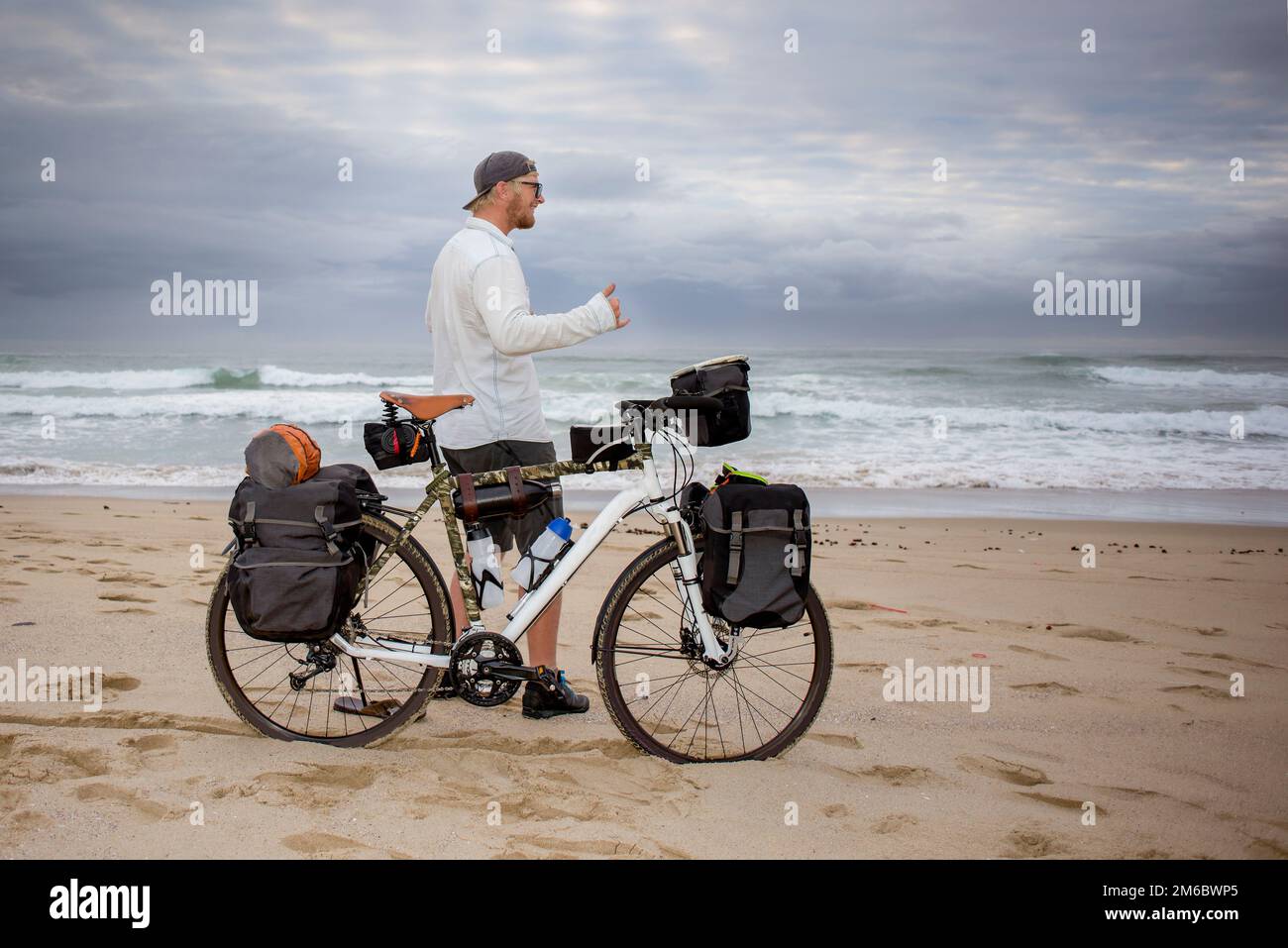 Young long distance cycle packer reaches the beach Stock Photo - Alamy