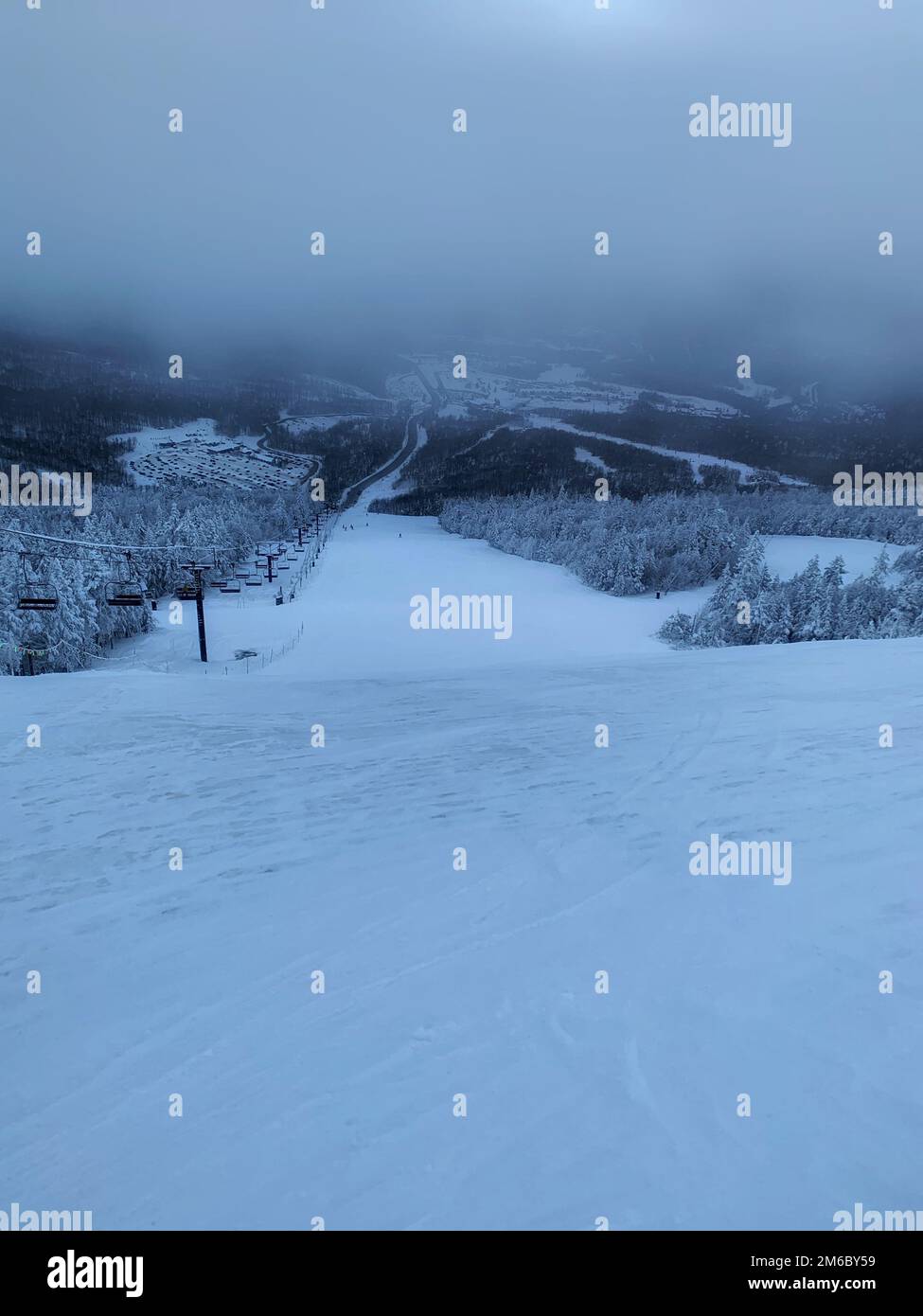 A vertical of a snowy road surrounded by trees in Killington Ski Resort ...