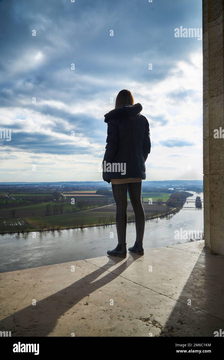 Young woman is looking into the landscape on a terrace with dramatic ...