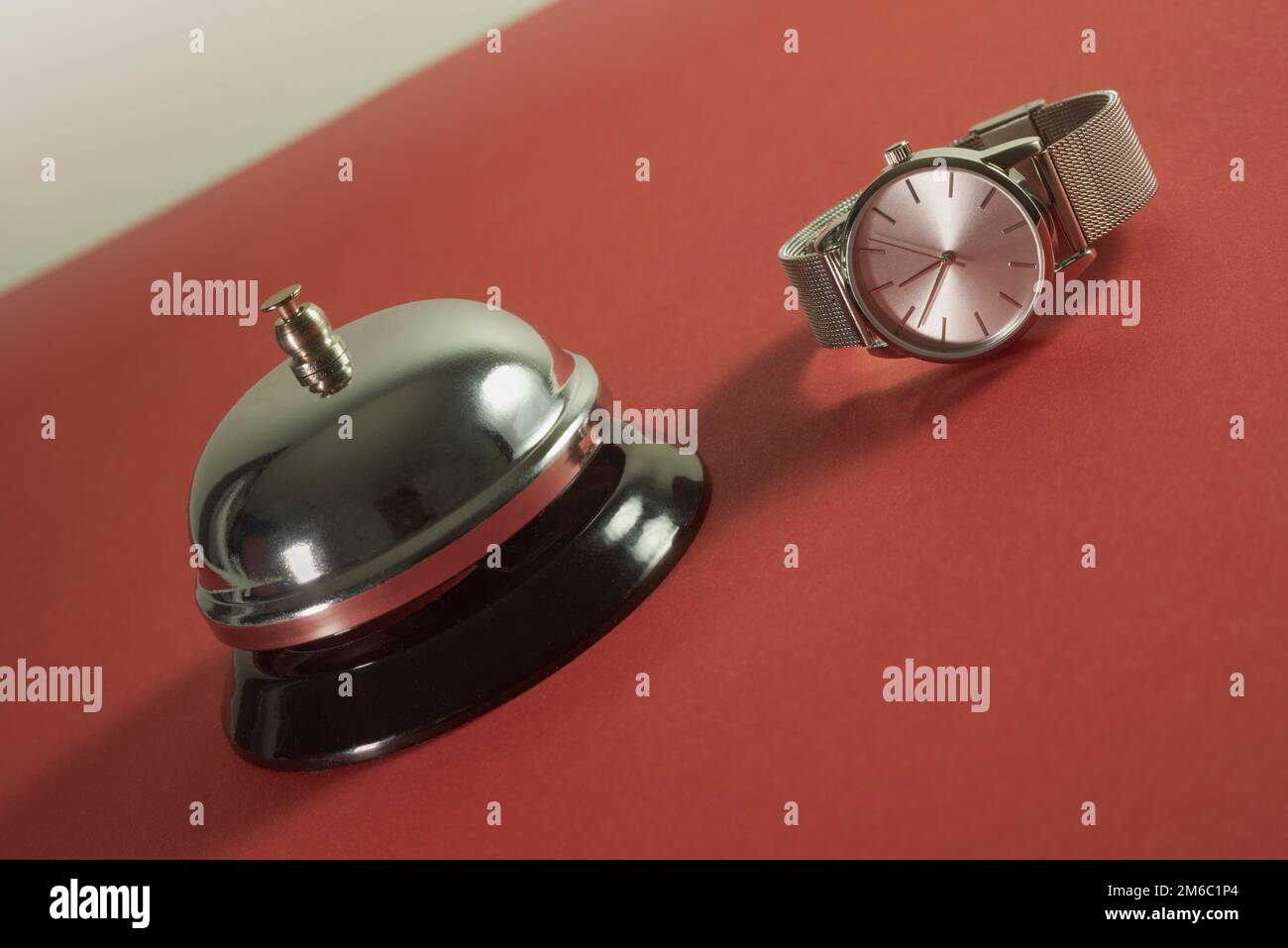 bell at the reception desk and wrist watch on a red background. time to ...