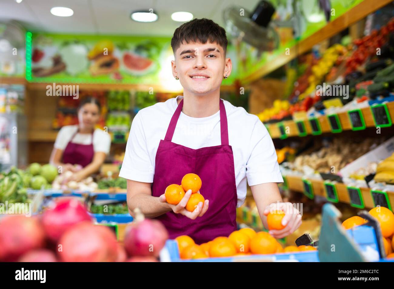 Man store employee displaying assortment of oranges at fruit department ...