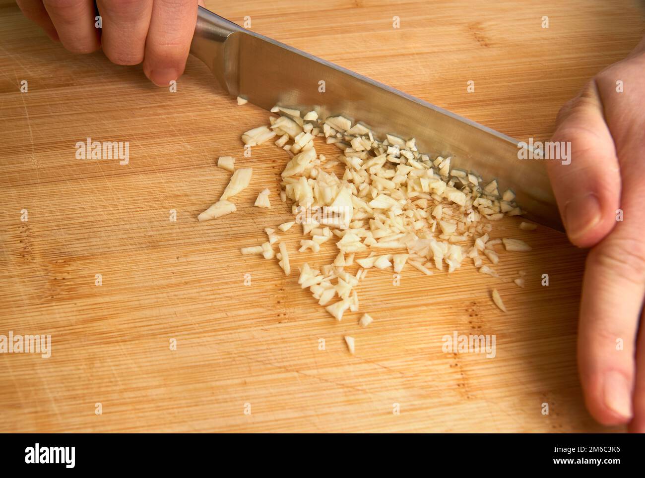 Man's hands cutting fresh garlic in the kitchen, preparing a meal for ...