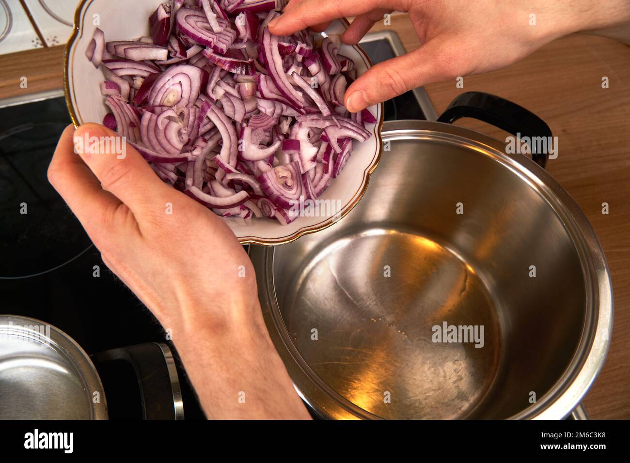 View on hands of a man roasting onions in a pot with coconut oil Stock ...