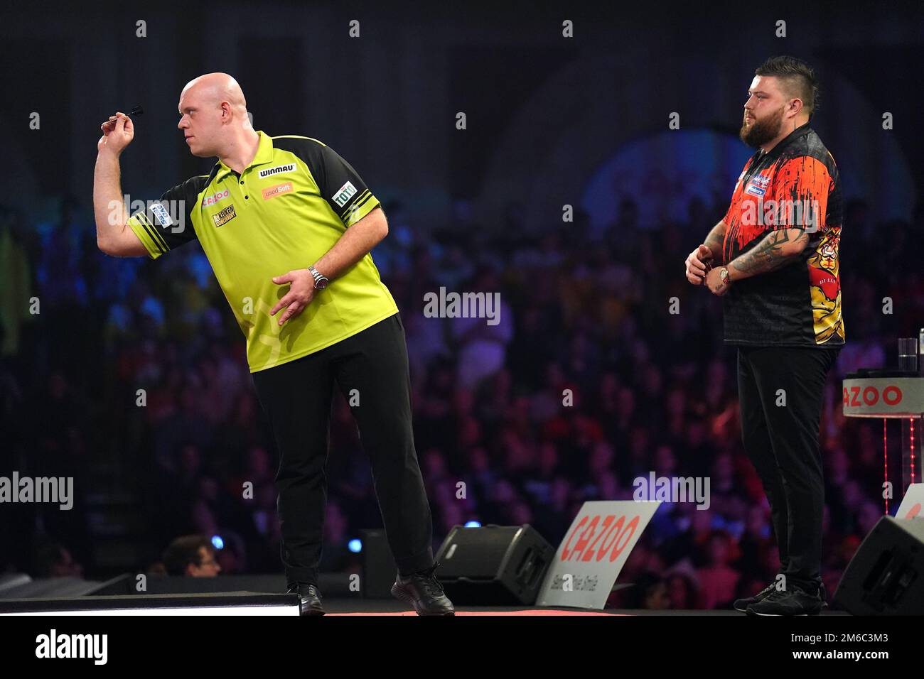 Michael van Gerwen (left) in action as Michael Smith looks on during the final of the Cazoo ...