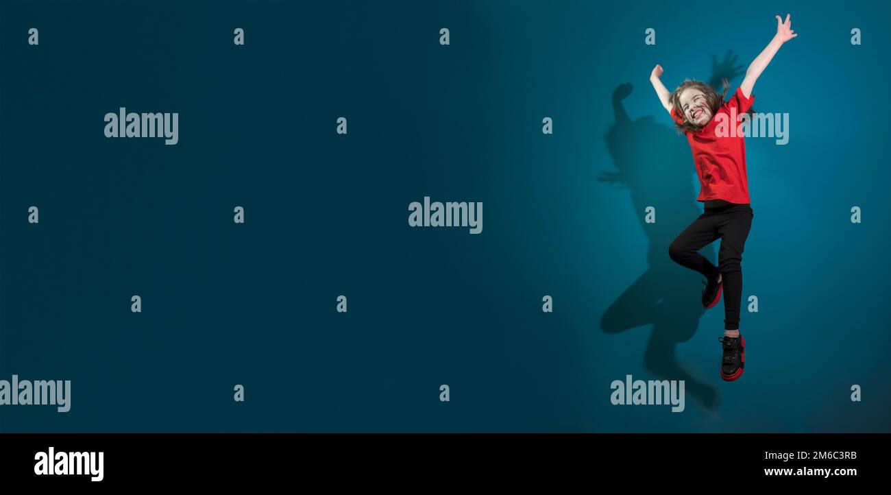 Joyful jumping girl in flight on turquoise background in sportswear ...