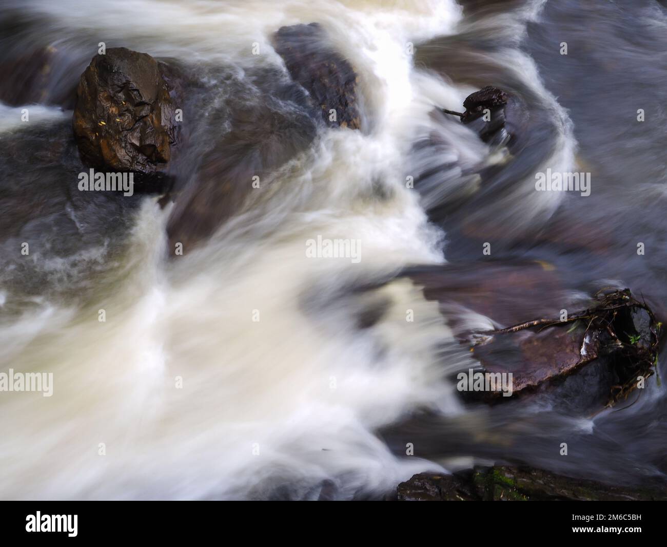 Strong current in river passing rocks, long exposure Stock Photo - Alamy