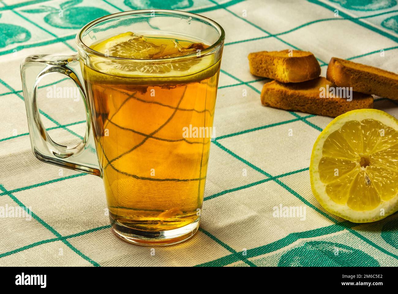 On the table is a glass of tea with lemon and lie vanilla biscuits ...