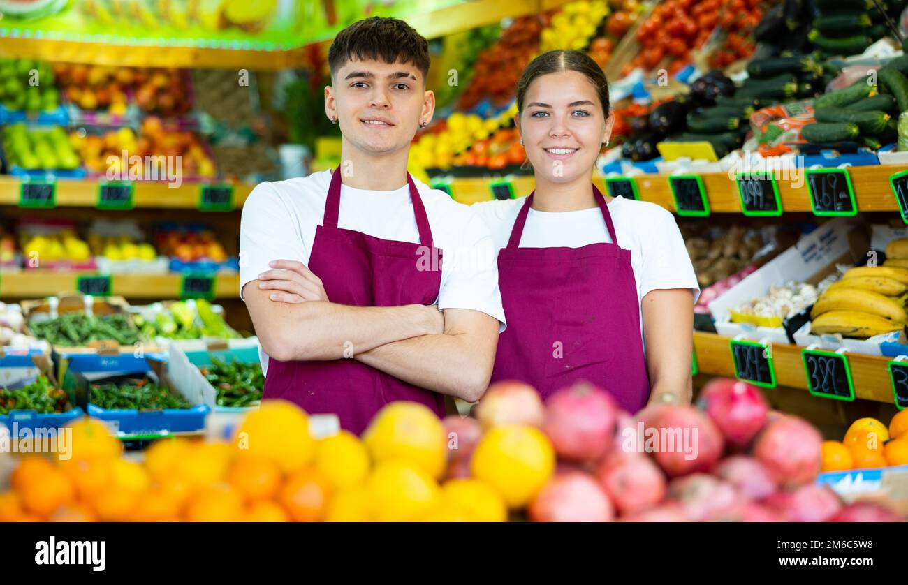 Young male and female sellers smiling at camera in fruit section of ...