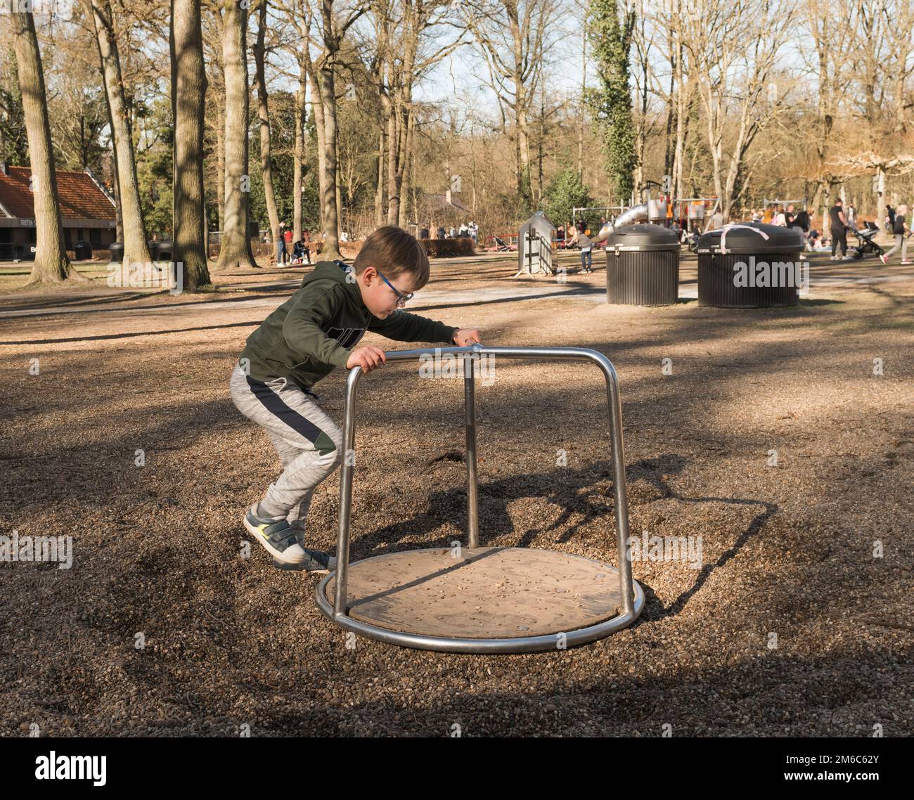 Boy riding a simple carousel in autumn park. Free time from school ...