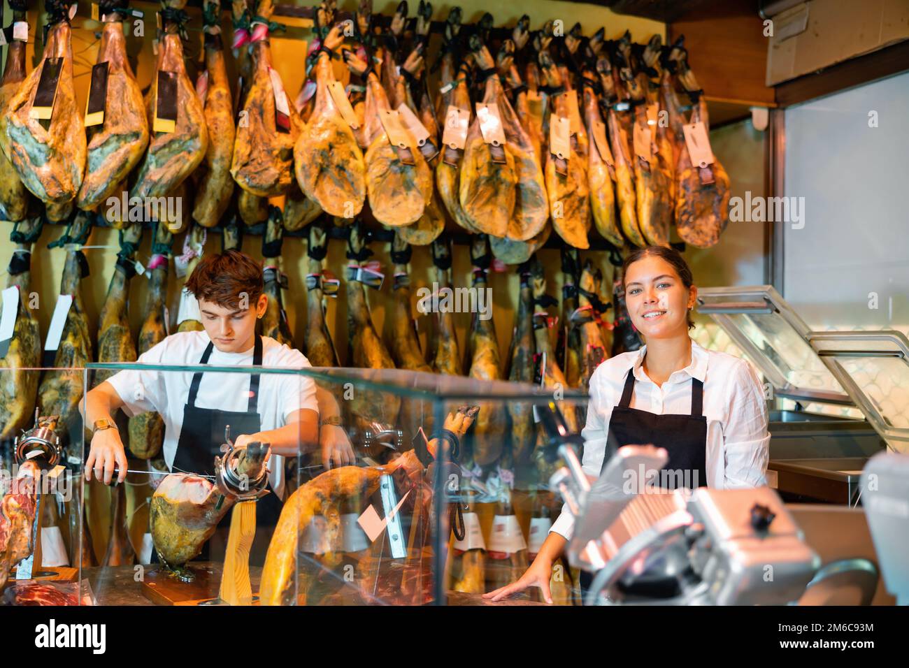 Young couple work together in butcher shop - they cut traditional ...