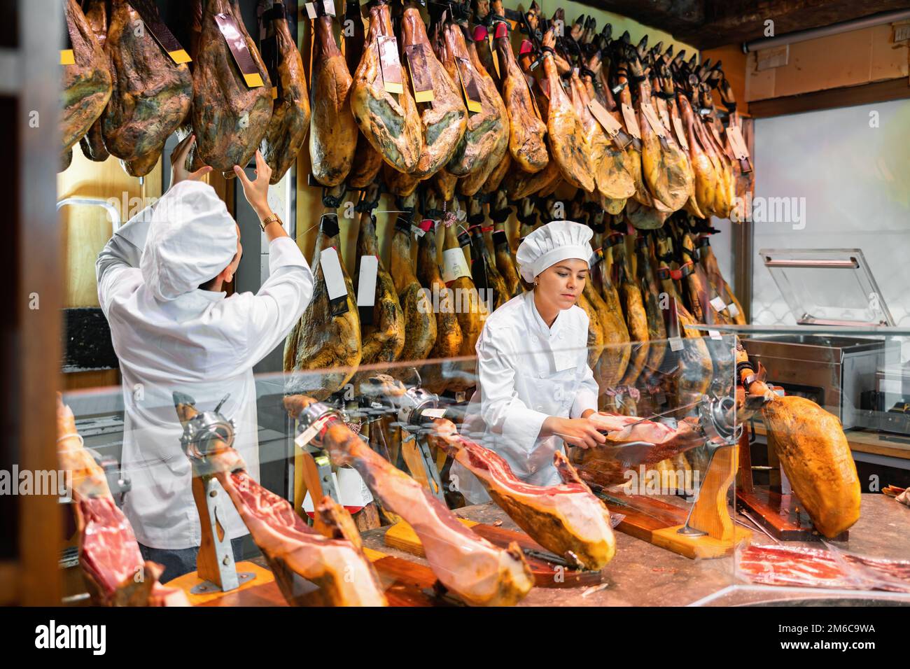 Young man and woman selling spanish jamon at counter Stock Photo - Alamy