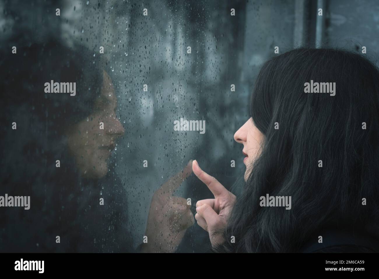 Woman looking on rainy window Stock Photo - Alamy