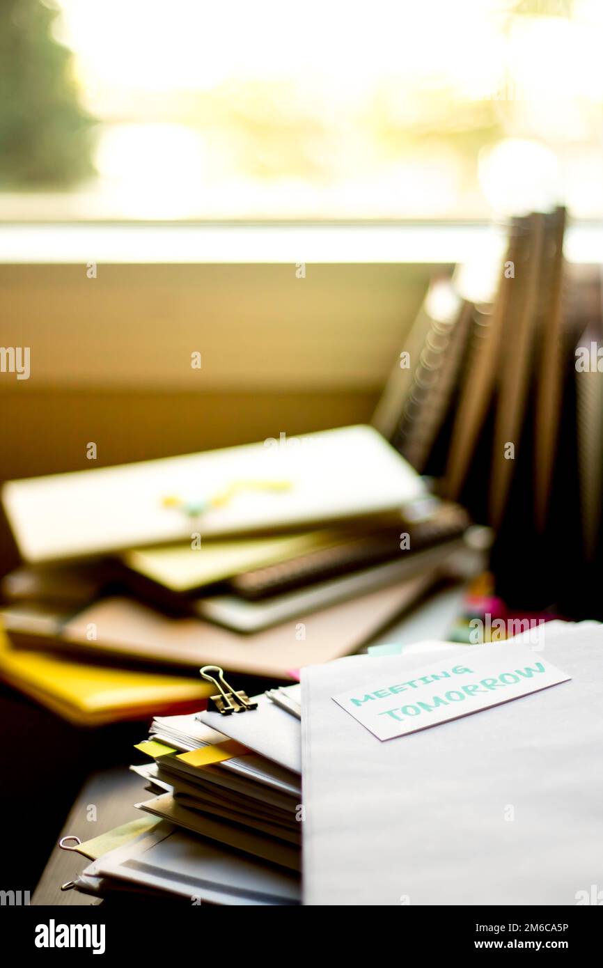 Meeting Tomorrow; Stack of Documents. Working or Studying at messy desk ...