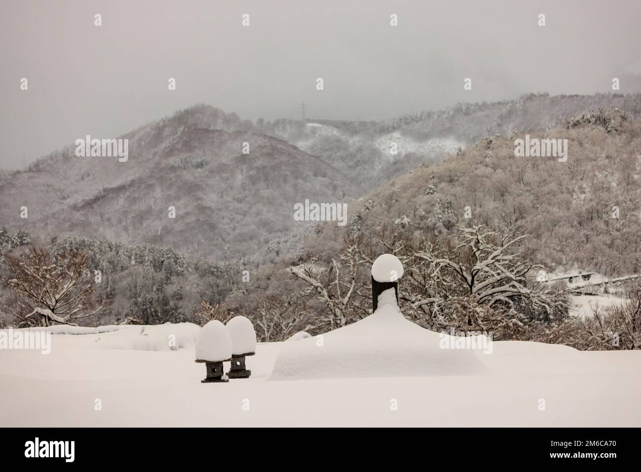 Snow piles on objects with forested mountain landscape in winter Stock ...