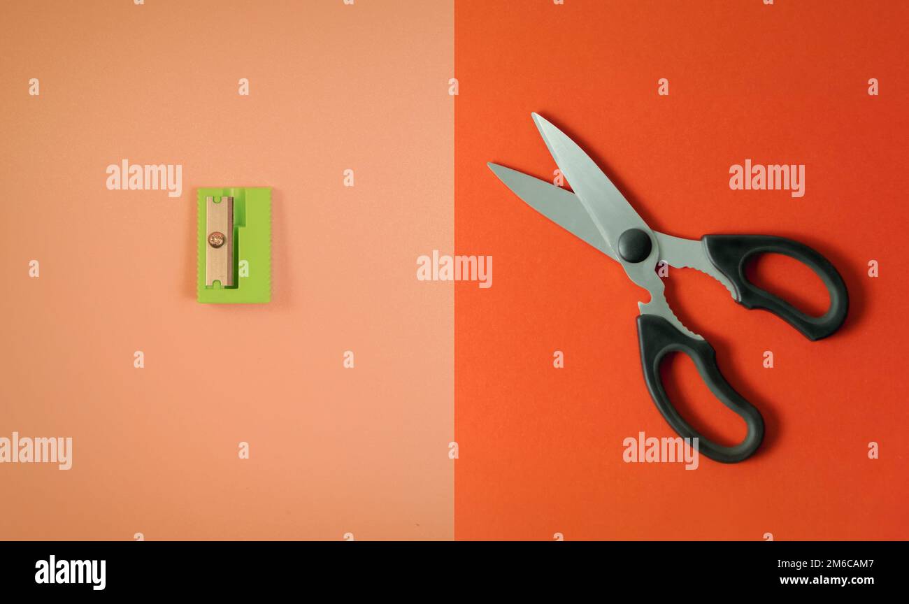 Scissors and pencil sharpener. red and pink background. flat layer ...