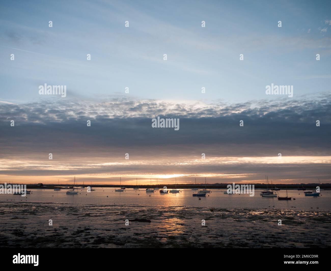 Sun set sky dramatic clouds sea front beach harbor marina boats moored ...